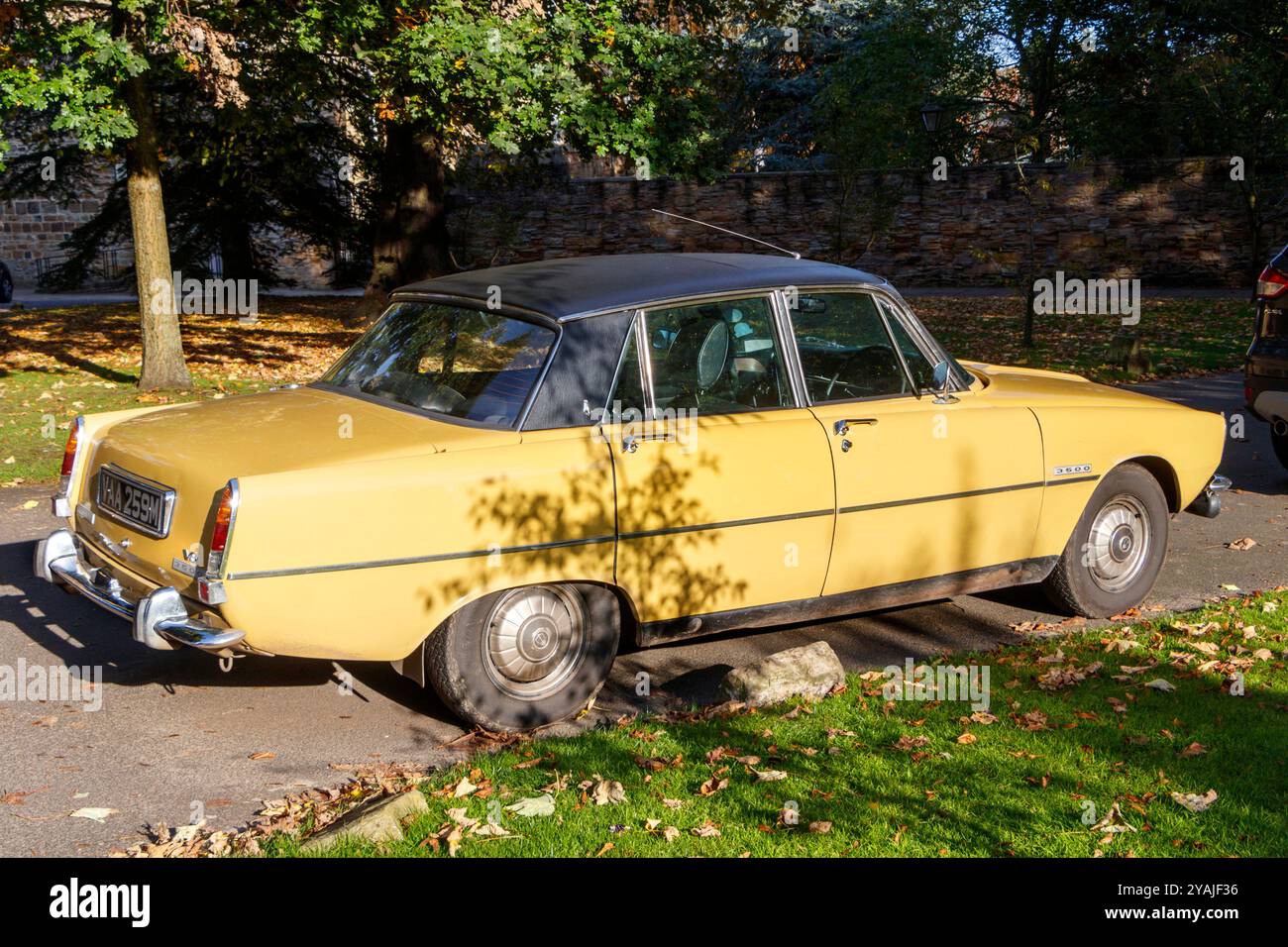 Vintage yellow Rover P6 3500 car parked on a quiet street with fallen ...