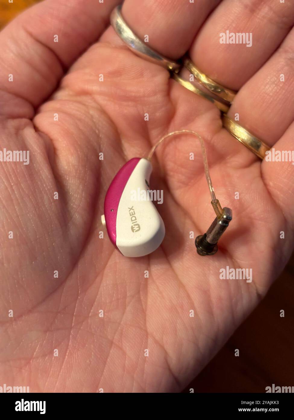 Pink widex hearing aid in a young hand Stock Photo - Alamy