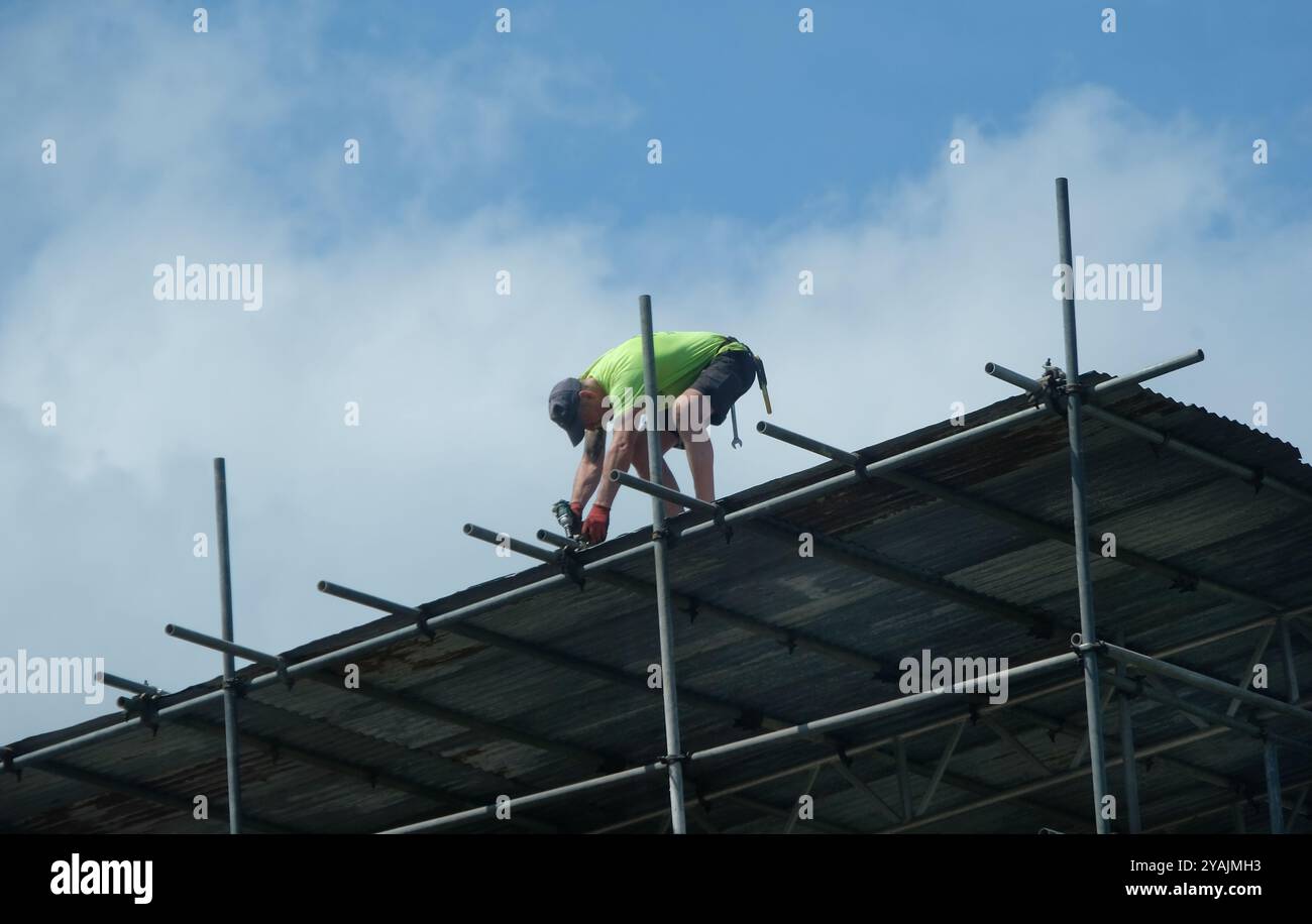A man, scaffolder, putting up scaffolding on a house roof Stock Photo ...