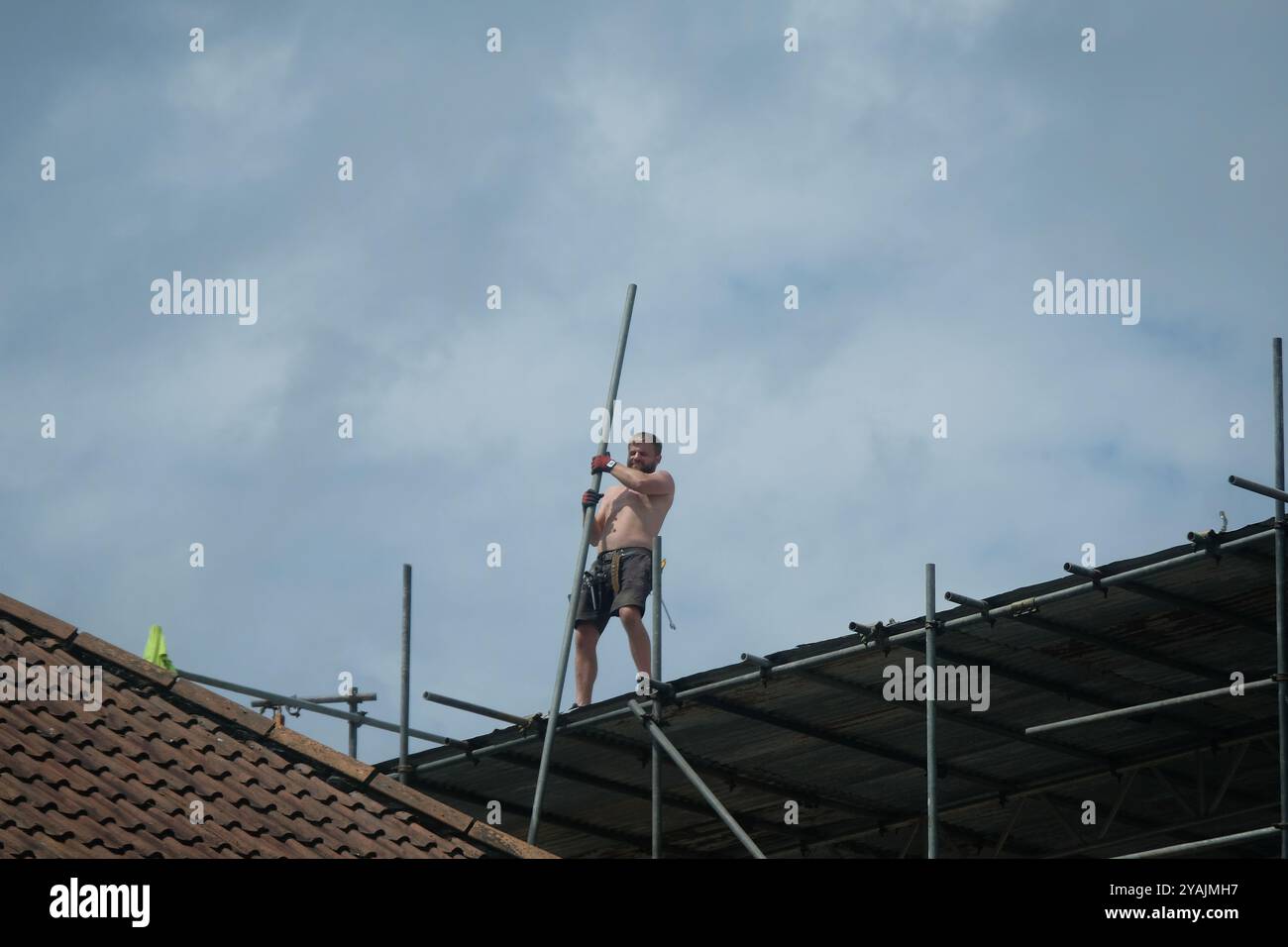 A man, scaffolder, putting up scaffolding on a house roof Stock Photo ...