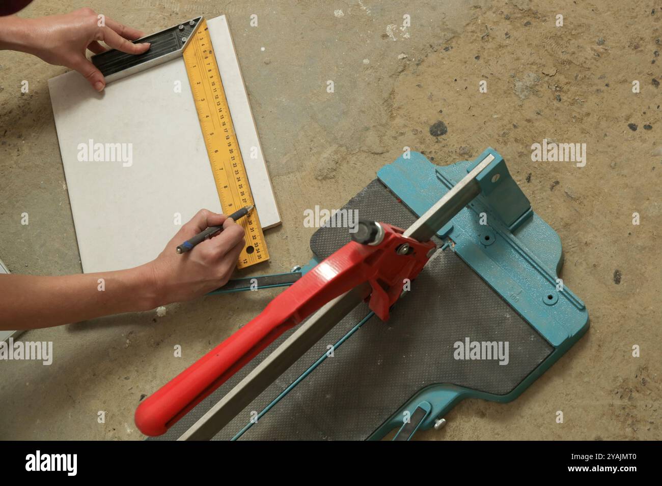 Woman doing measurements and cutting tiles with a standard manual tile ...