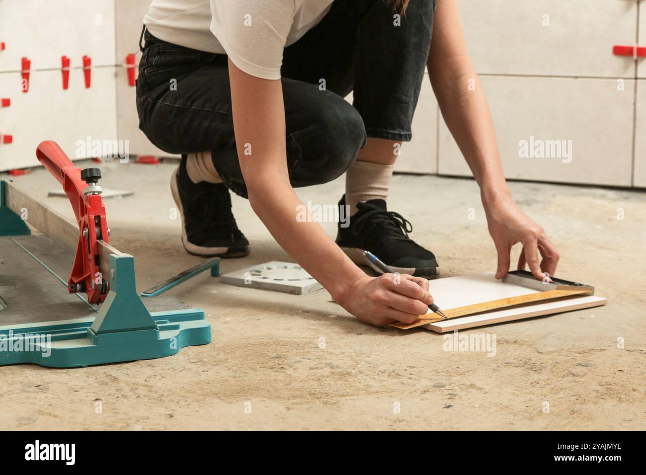 Woman doing measurements and cutting tiles with a standard manual tile ...