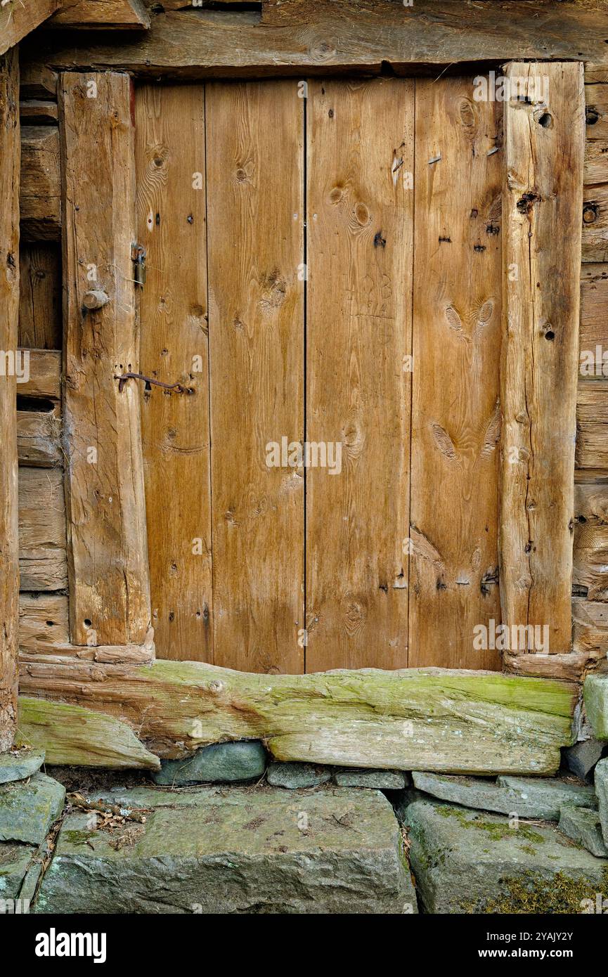 An old, wooden door with horizontal planks and a metal latch is set ...