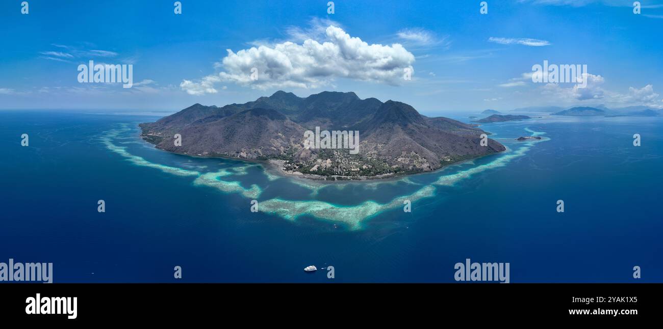 A beautiful and healthy coral reef surrounds a volcanic island off the ...