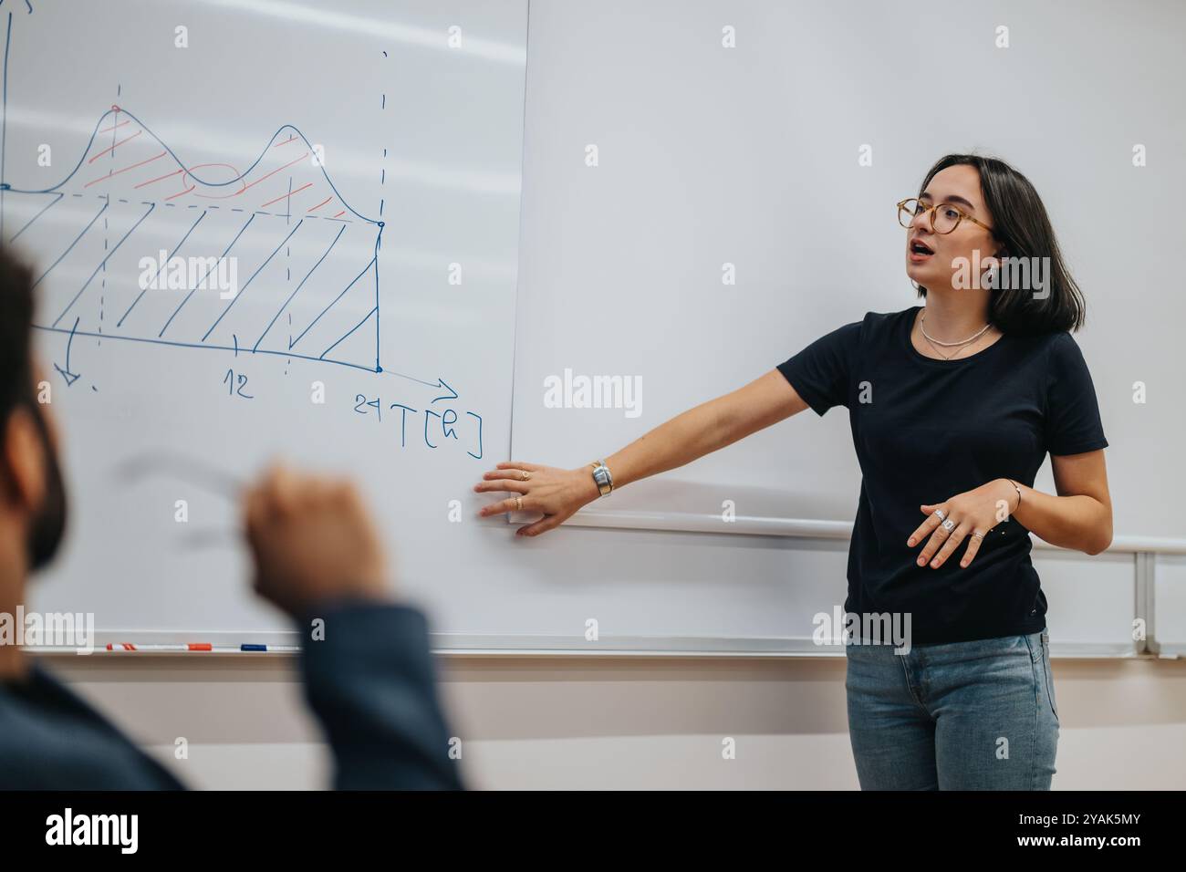 Student presenting graph data on whiteboard during classroom session ...