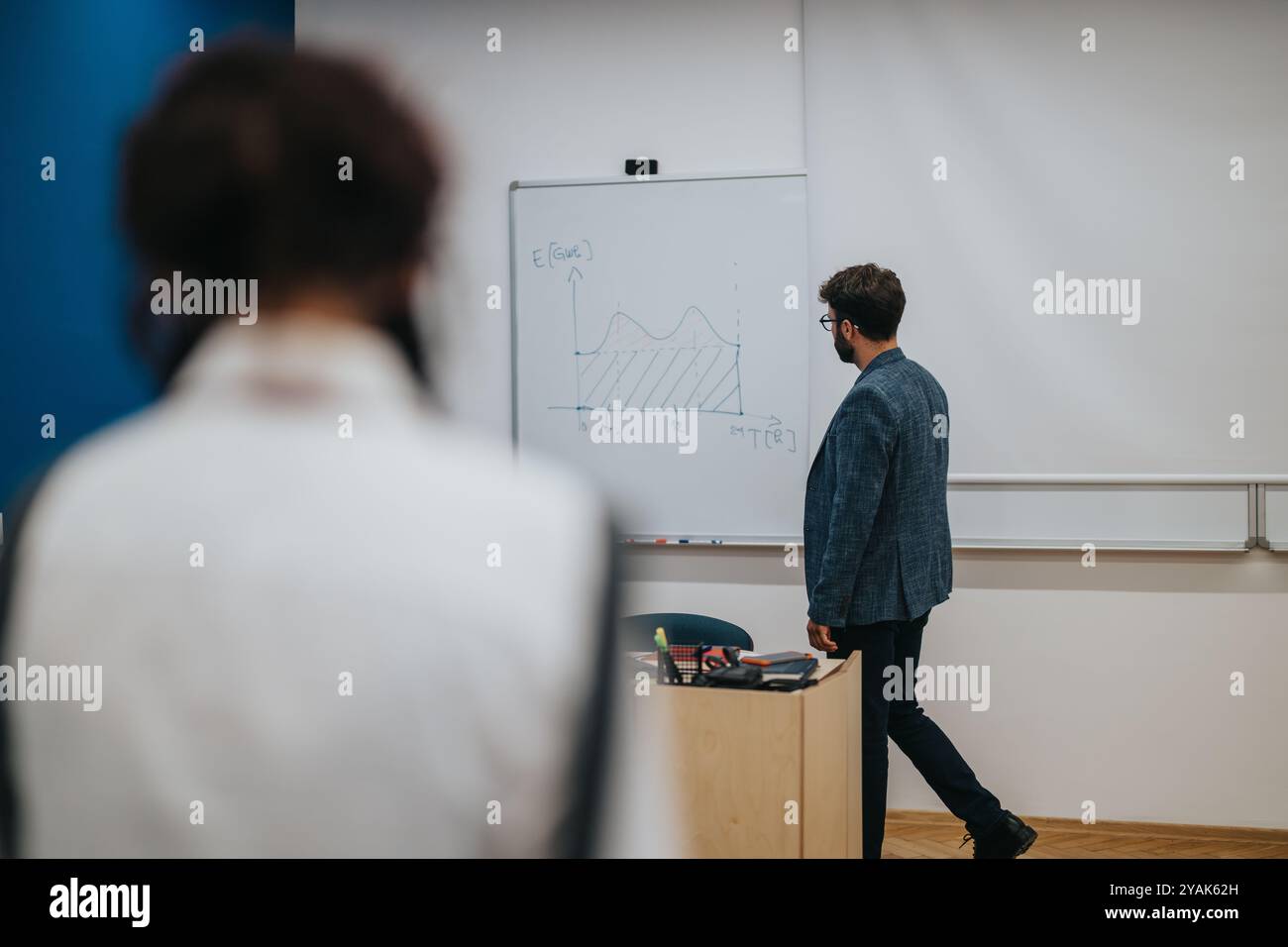 Teacher explaining graph on whiteboard during classroom lesson Stock ...