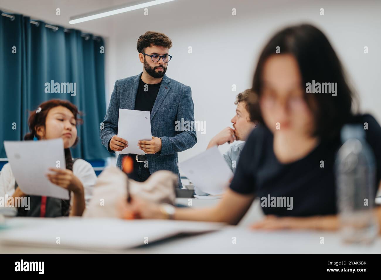 Professor guiding students in classroom during group exercise session Stock Photo - Alamy