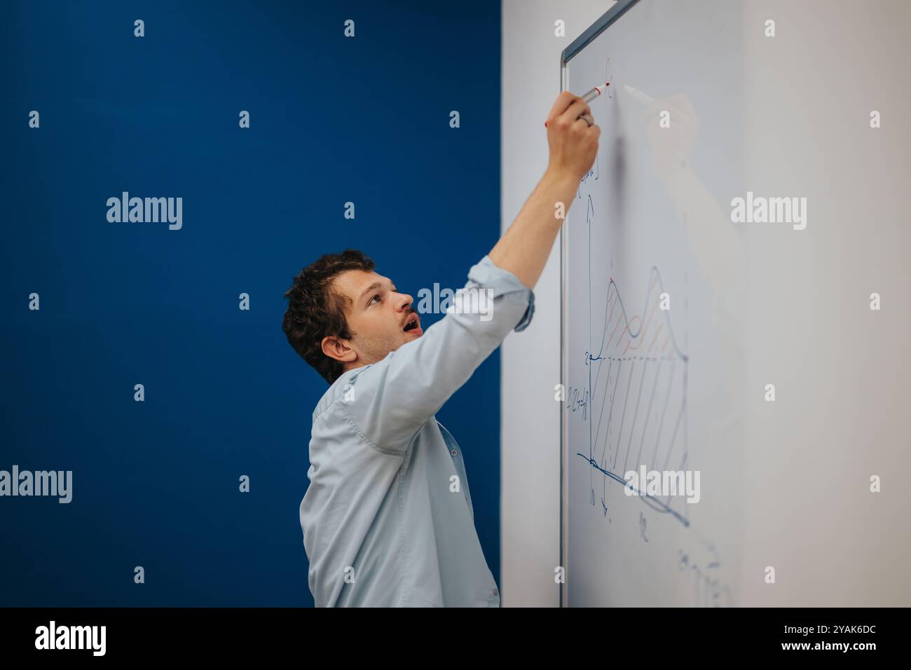 Teacher explaining graph on whiteboard during classroom lecture Stock ...