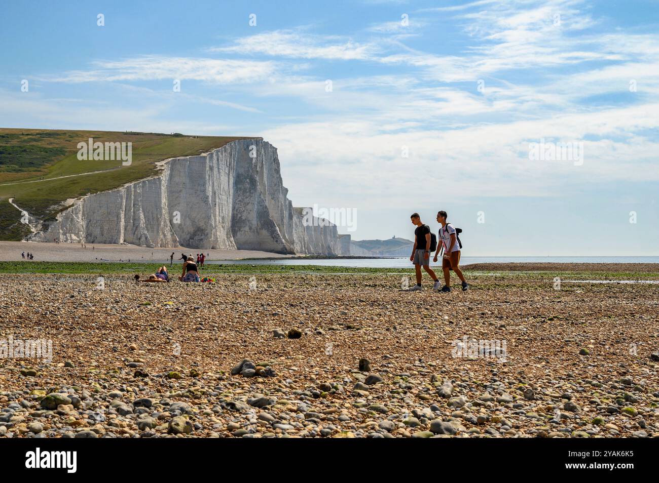 People enjoy the sunshine on Cuckmere Haven beach in front of the Seven Sisters and their chalk ...
