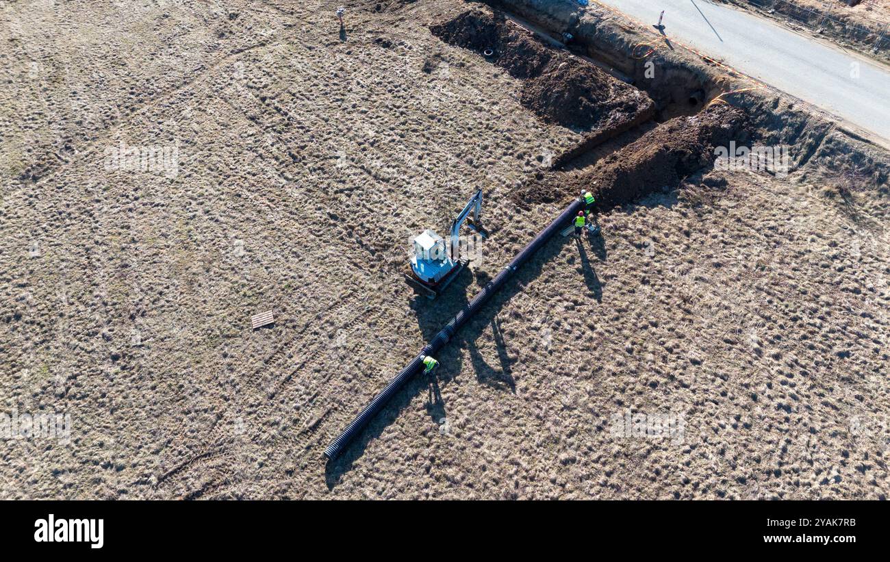 Aerial view of construction workers and an excavator installing a ...