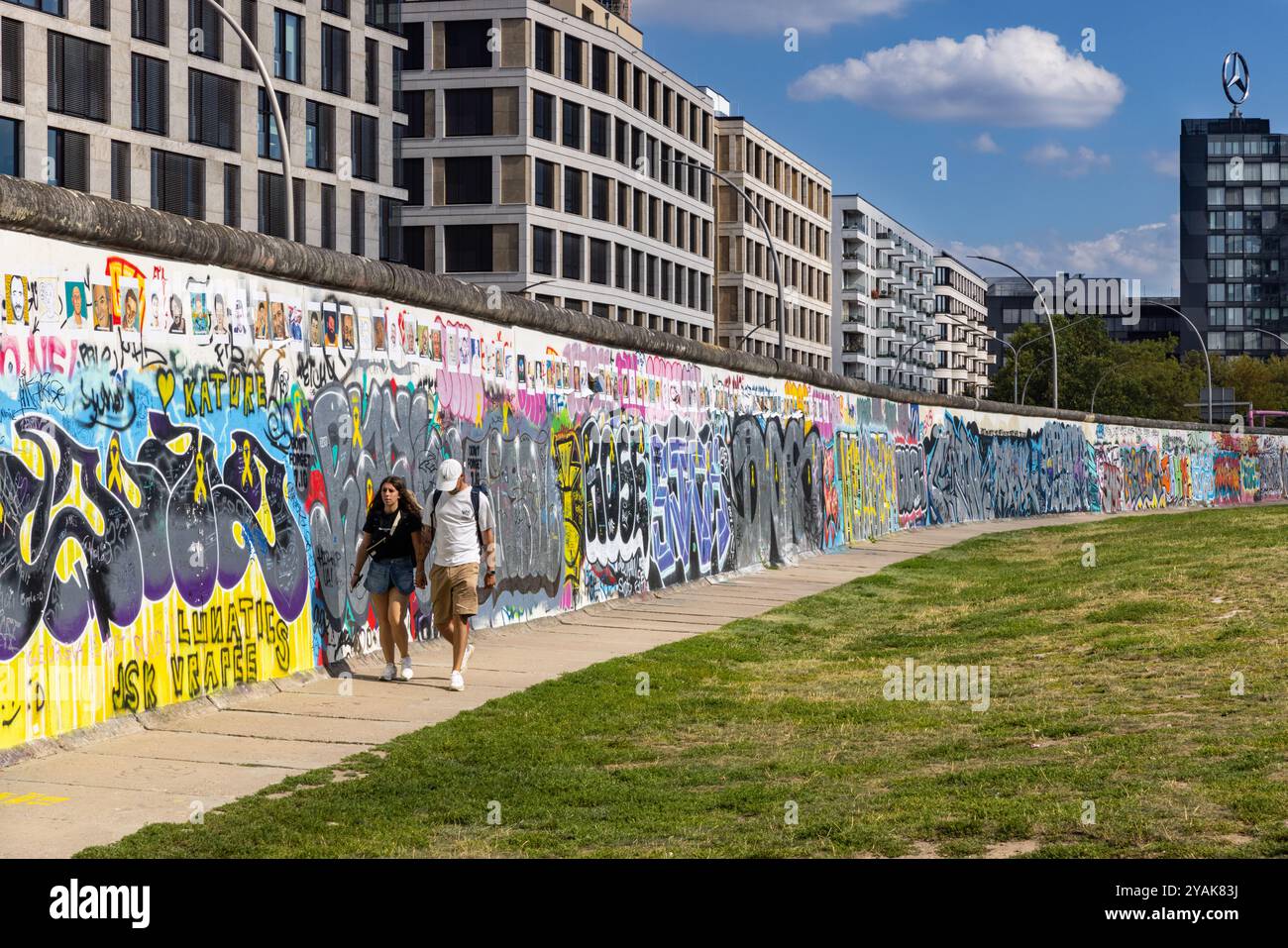 People walk along the back side of the East Side Gallery part of the ...