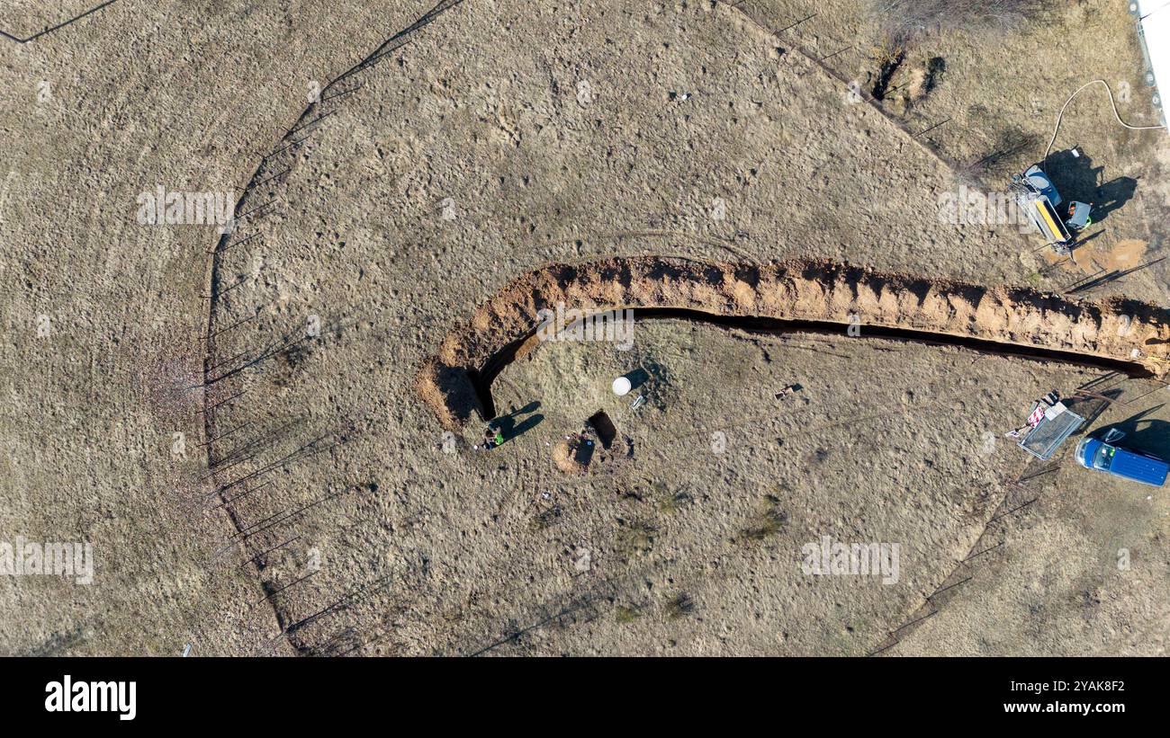 Aerial view of construction workers digging a trench in a field during ...