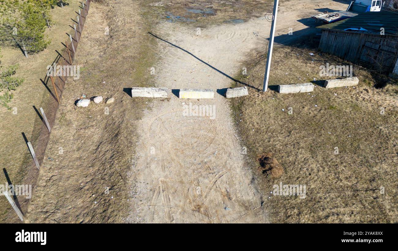 Aerial view of a rural dirt road blocked by concrete barriers, with a ...
