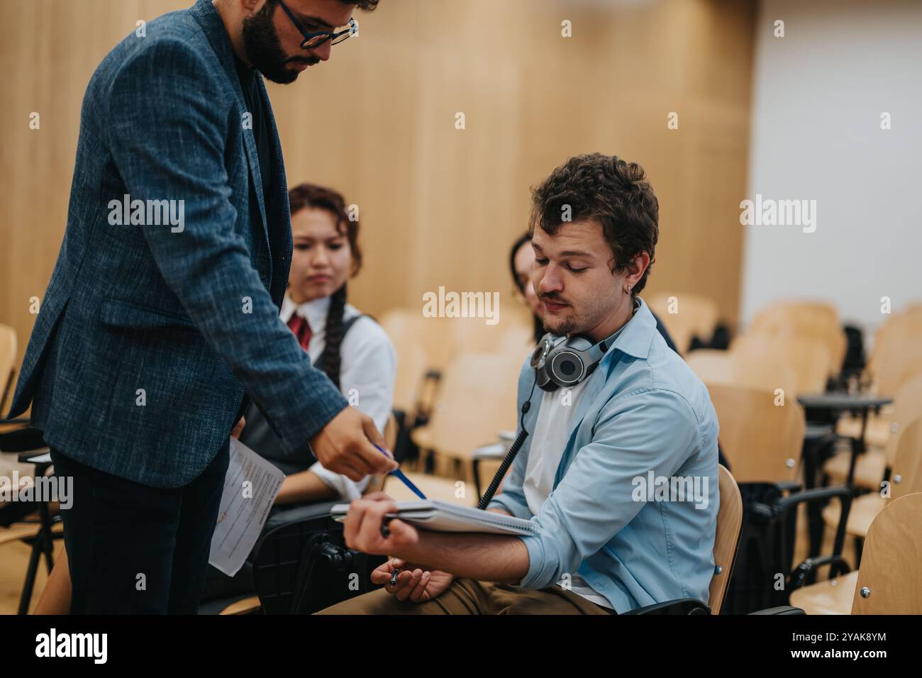 Professor consulting with college students in a classroom setting Stock ...