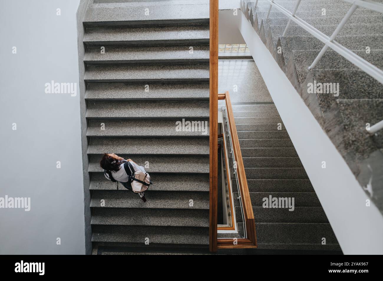 Student walking up staircase in bright modern building Stock Photo - Alamy