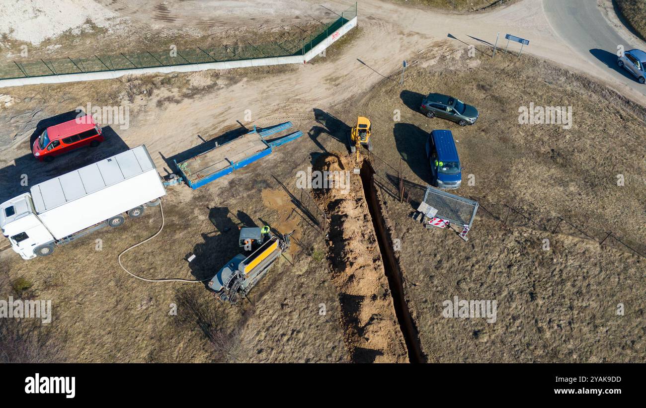 Aerial view of construction workers digging a trench in a field during ...