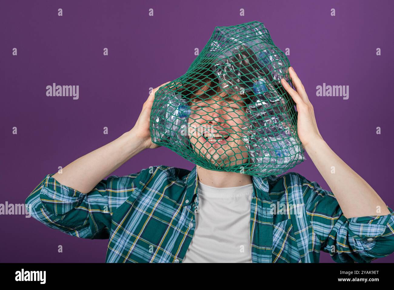 Young activist is covering his head with a recycling net full of ...