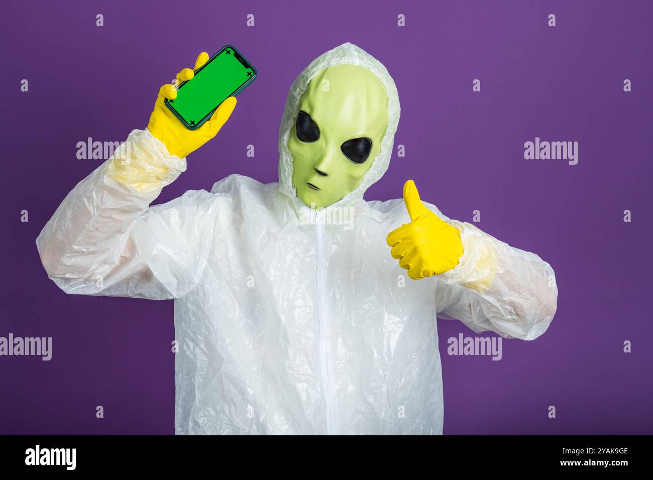 Person wearing a protective suit and an alien mask is holding a ...