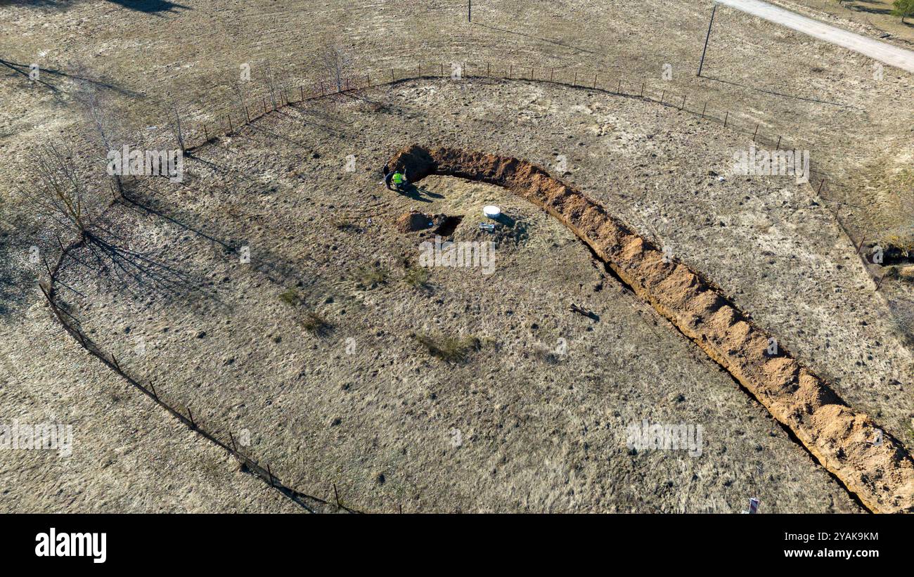 Aerial view of construction workers digging a trench in a field during ...