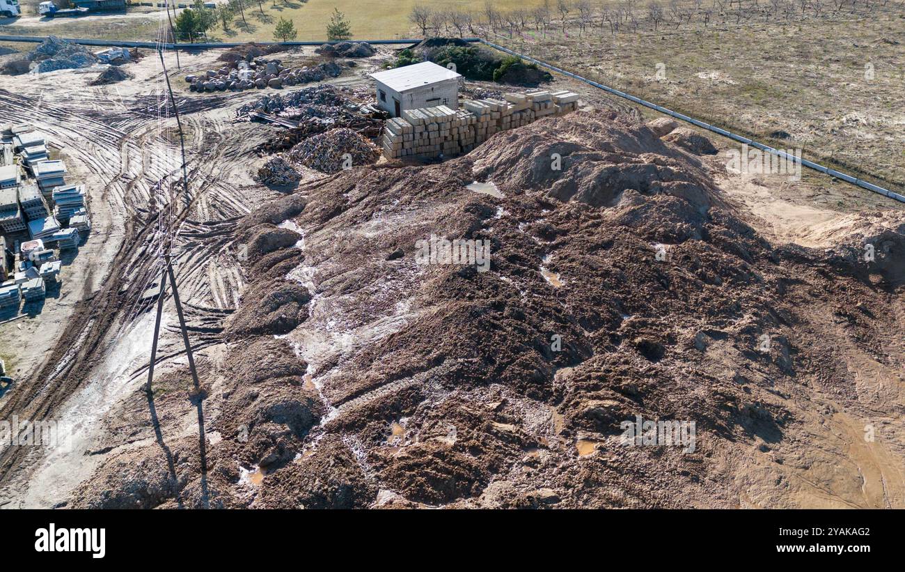 Aerial view of a storage site with piles of dirt, rocks, and building ...