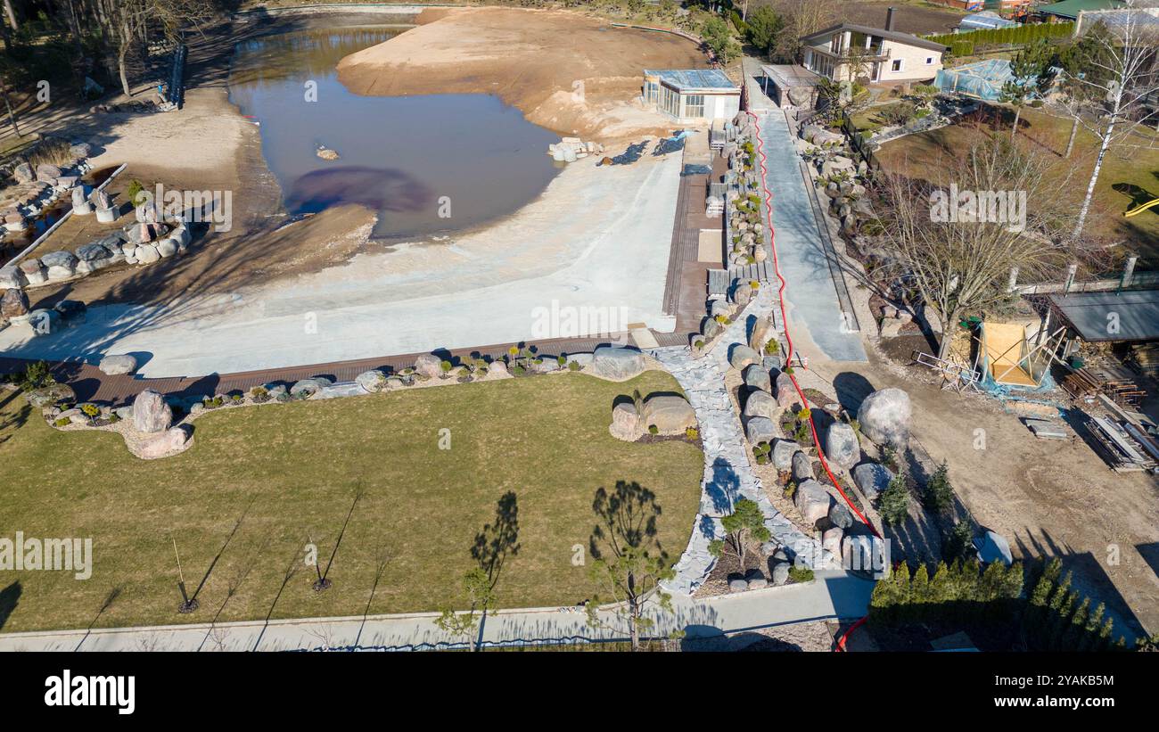 An aerial view of a construction site near a pond. The area shows a mix ...