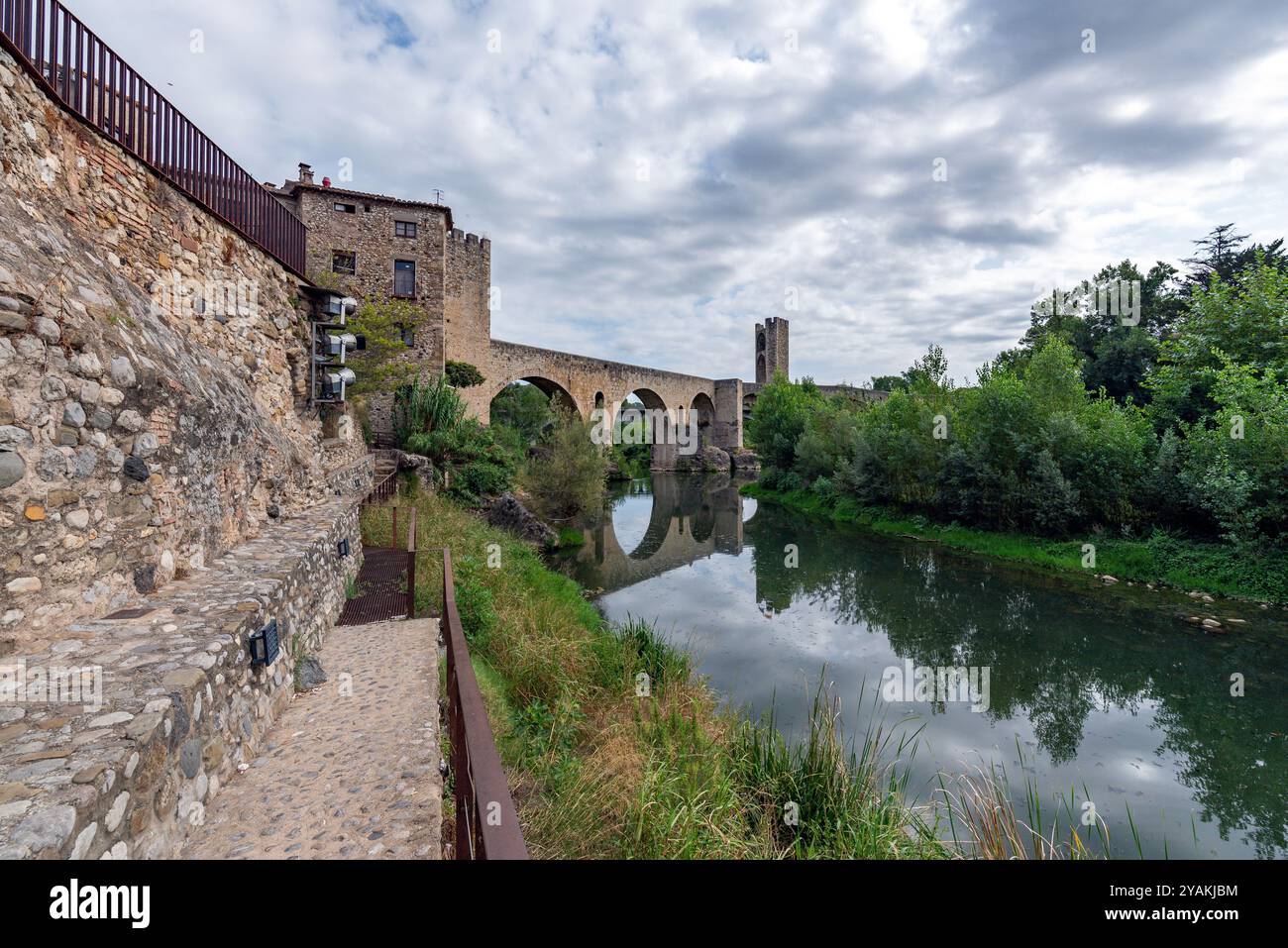Medieval bridge formed by several arches with a river and a cloudy sky ...