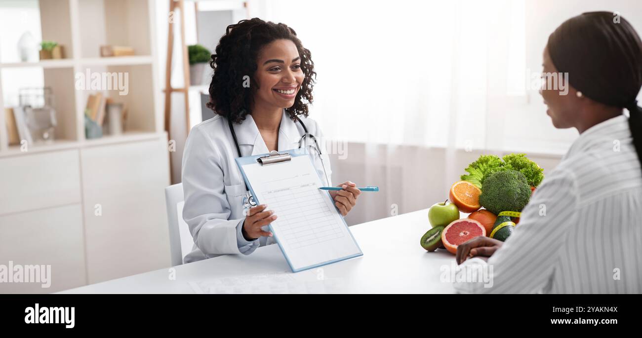 Positive dietologist showing patient medical chart while consultation ...
