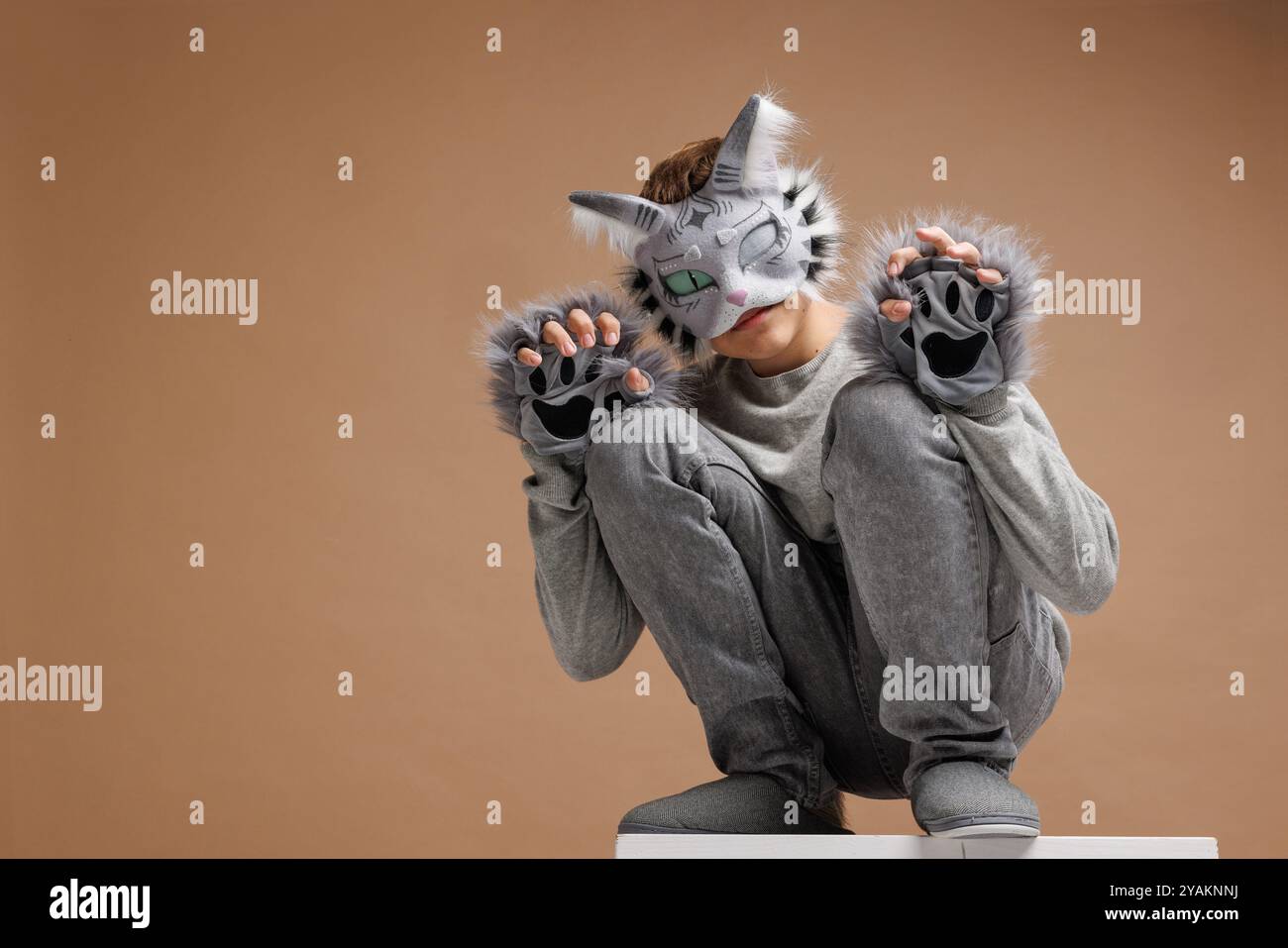 quadrobics portrait, Teenager in cat mask on beige background, studio ...