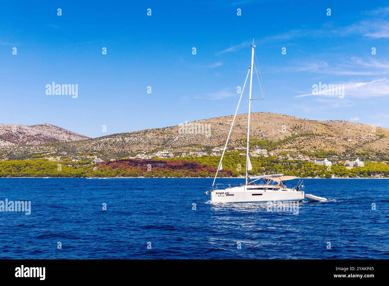 Sailboat motoring along the Croatian coast with Medena in background ...