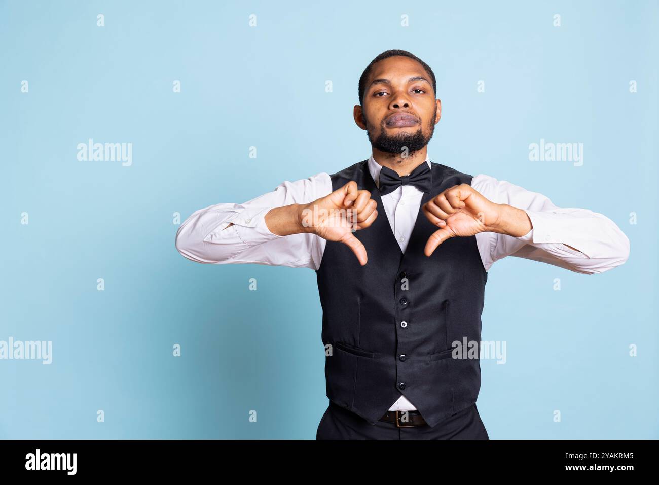 Discontent unhappy bellhop gives a thumbs down symbol on camera ...