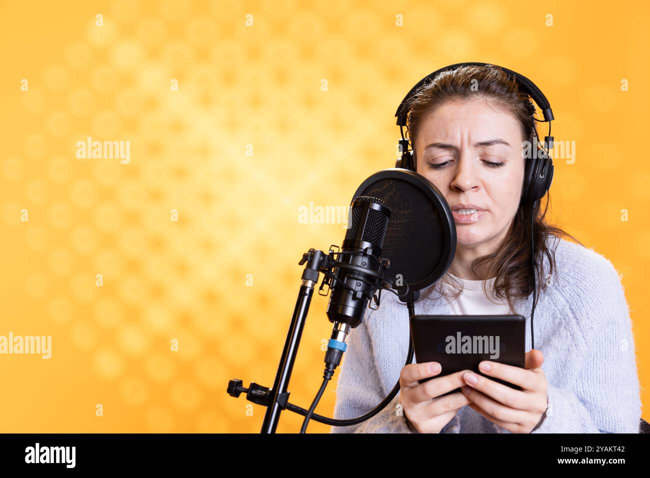 Voice actor frowning while reading ebook from ereader, recording ...