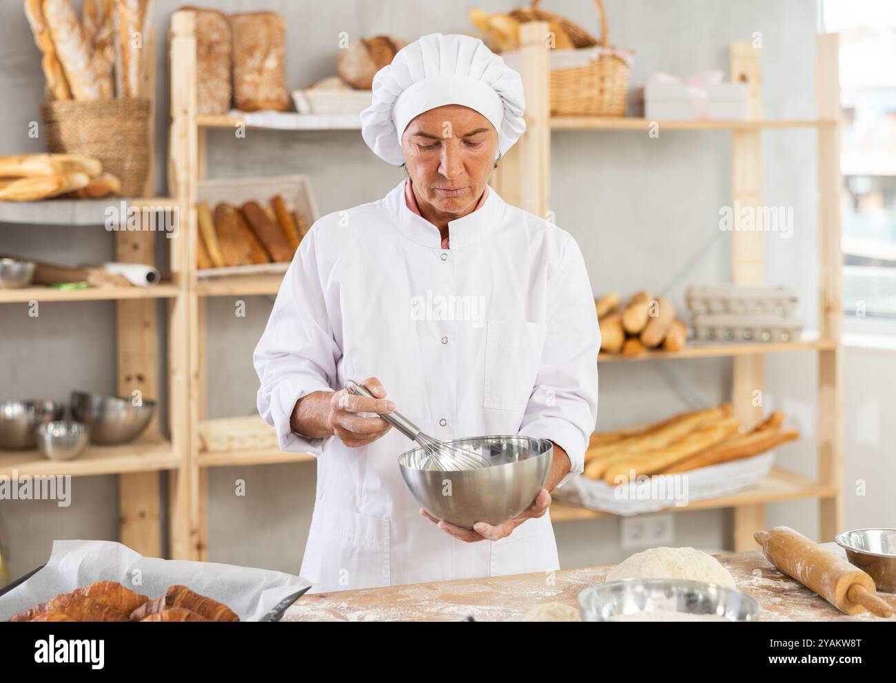 Mature woman baker mixing ingredients for dough Stock Photo - Alamy