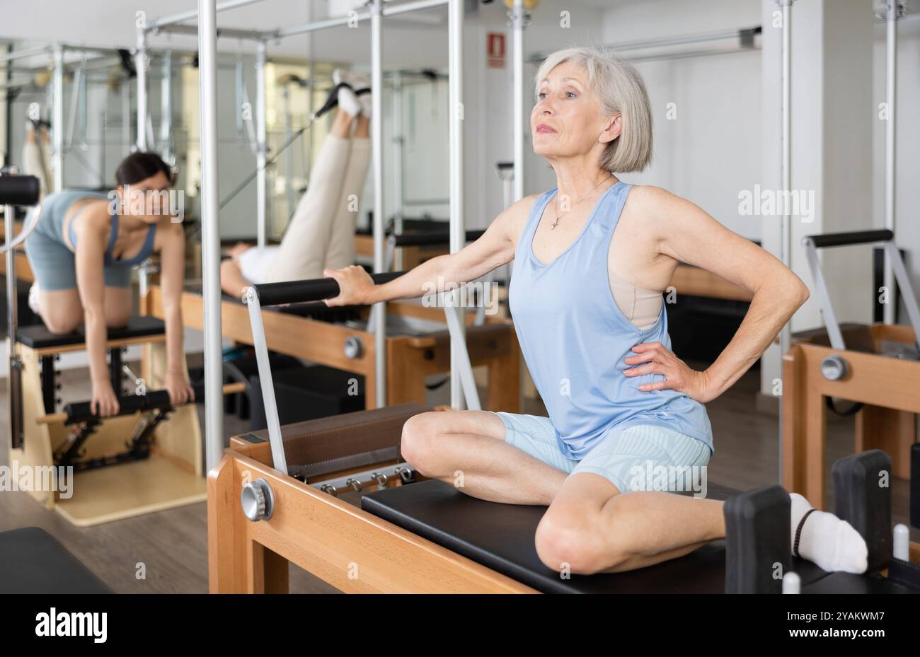 Elderly woman performing set of pilates exercises on reformer Stock ...