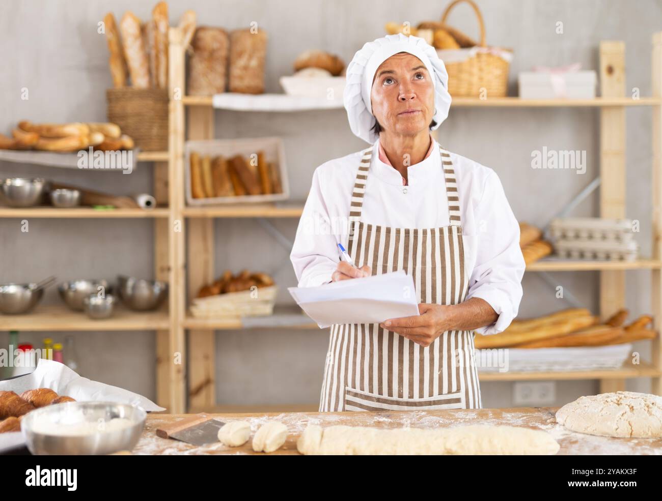 Female baker taking notes on available ingredients in bakery Stock ...