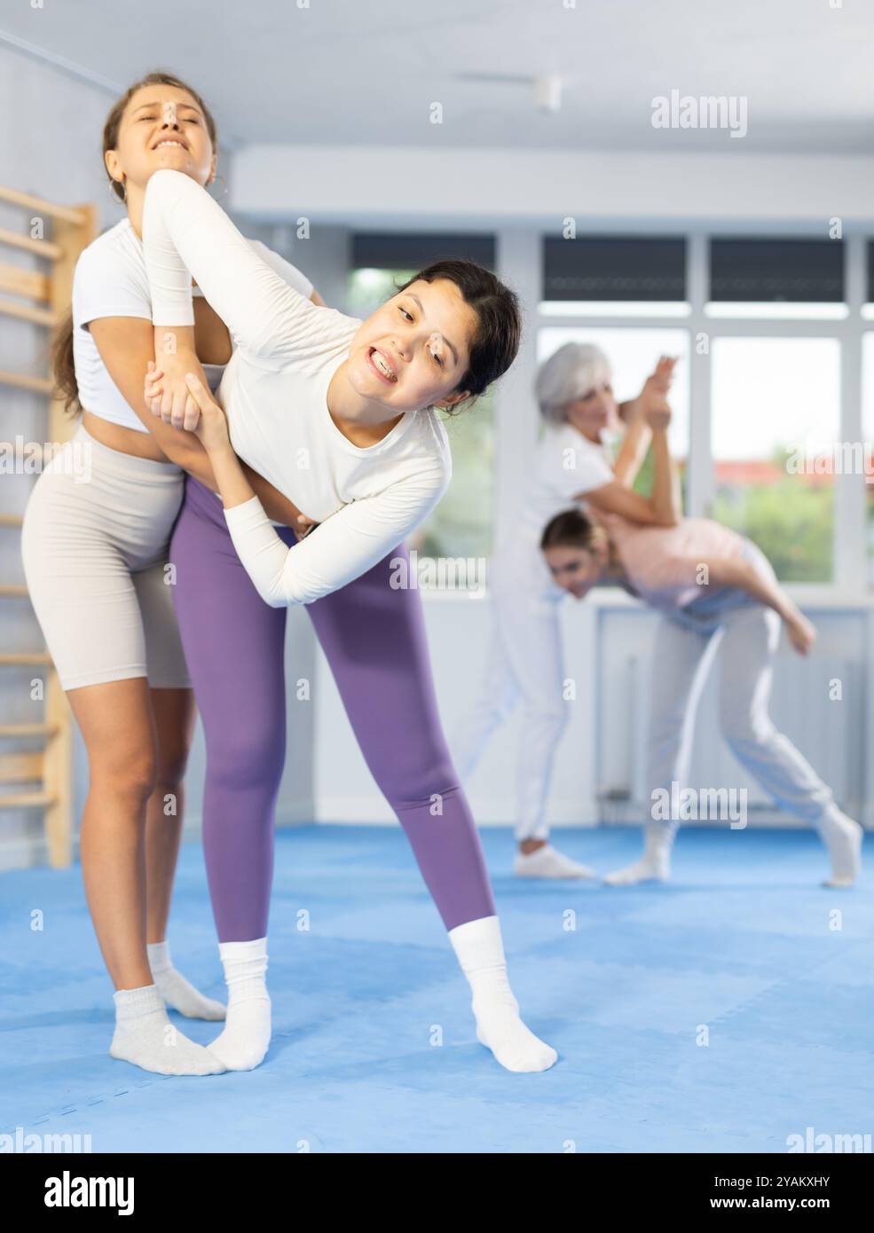 Woman and girl in gym perform basic elements of krav maga self-defense ...