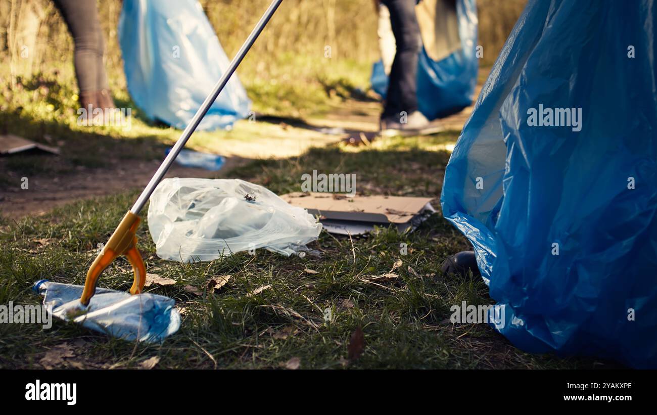 Volunteer using tongs tool to collect trash and plastic waste from the ...