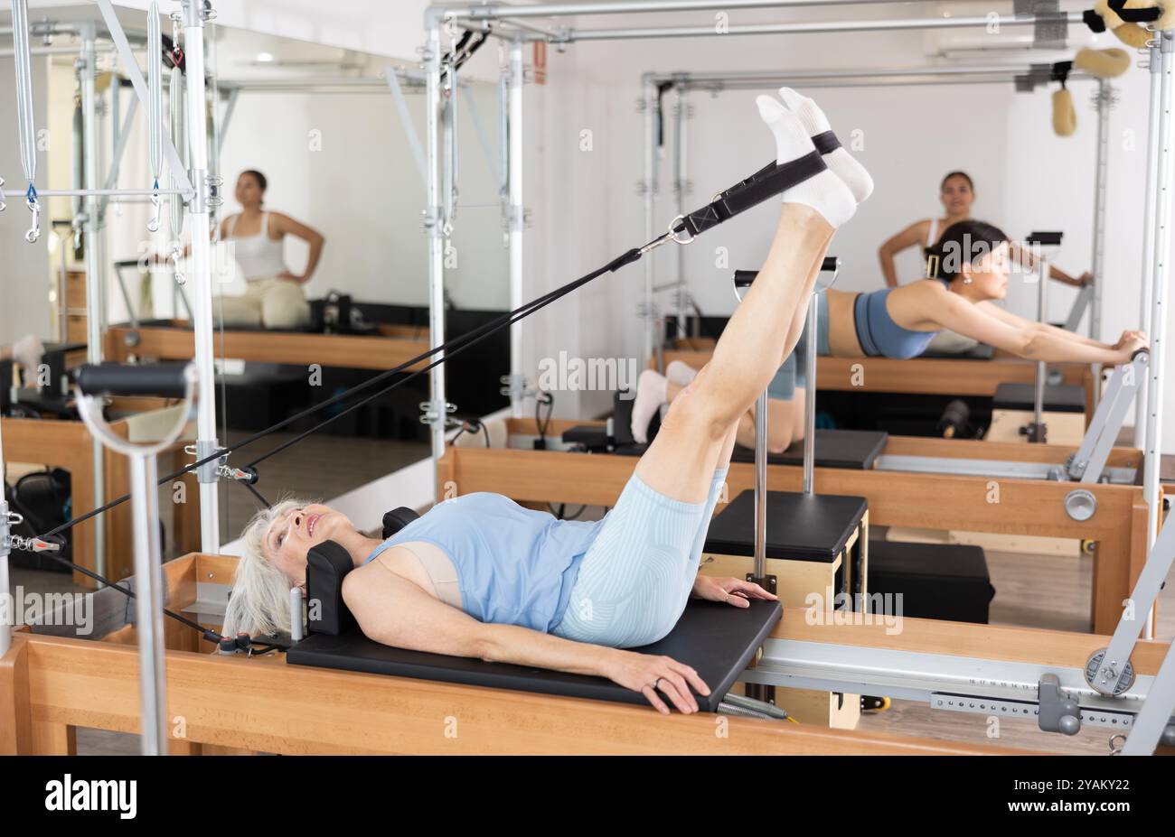 Elderly woman performing set of pilates exercises on reformer Stock ...
