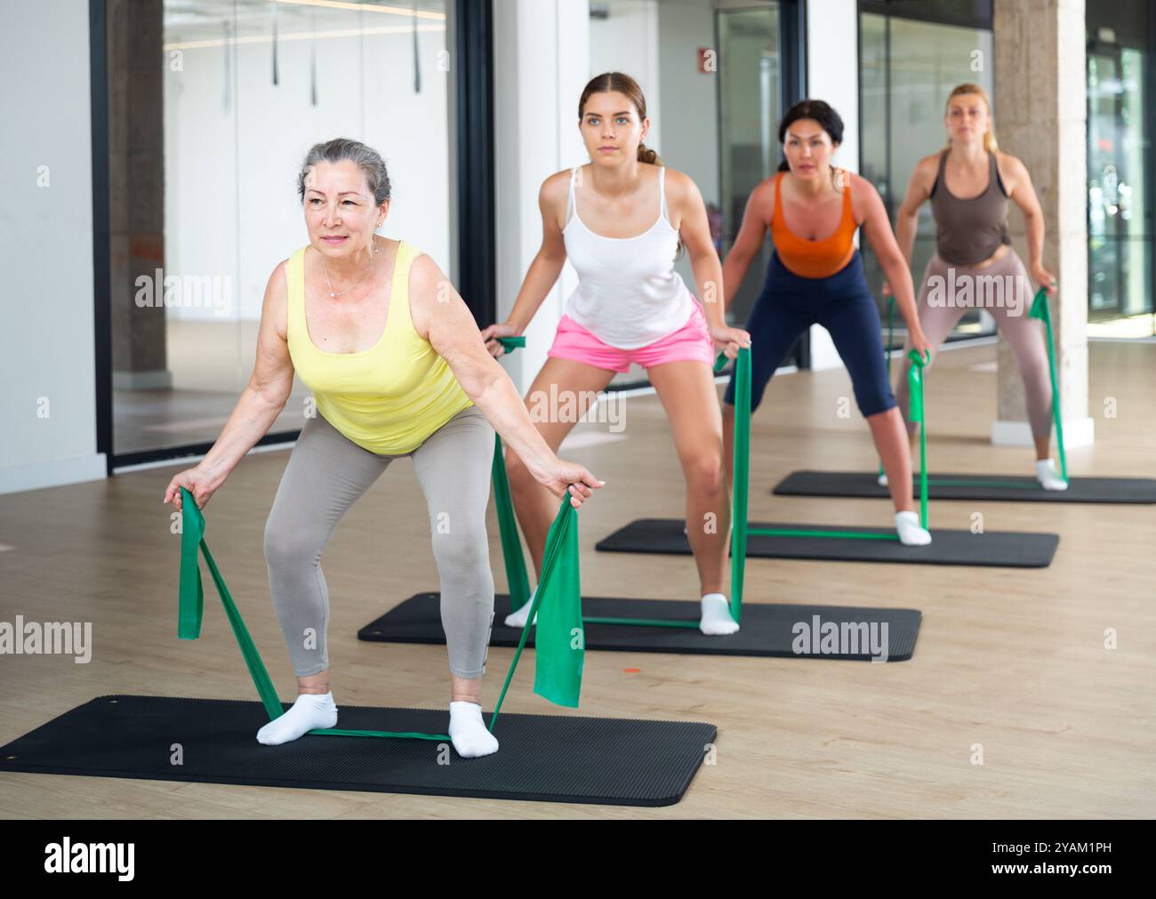 Women are doing stretching exercise with green resistance bands ...