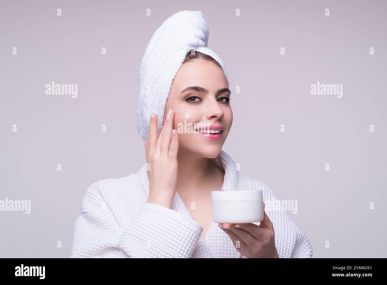 Skin care. Beauty portrait of a beautiful woman applying face cream ...