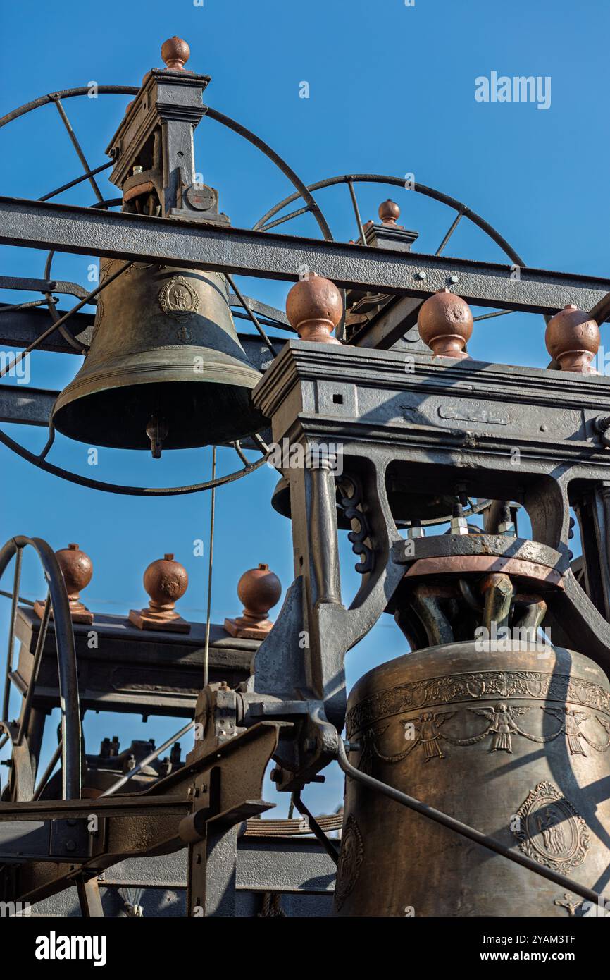 Intricate church bells hang in metal frame against blue sky, showcasing ...