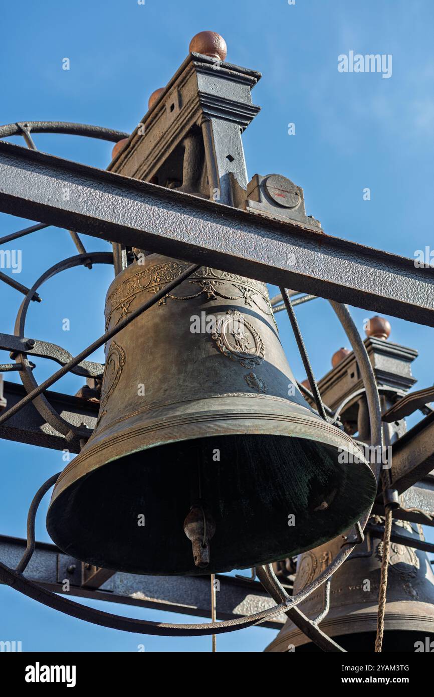 Large bronze bell with ornate carvings hanging in a bell tower, showing ...