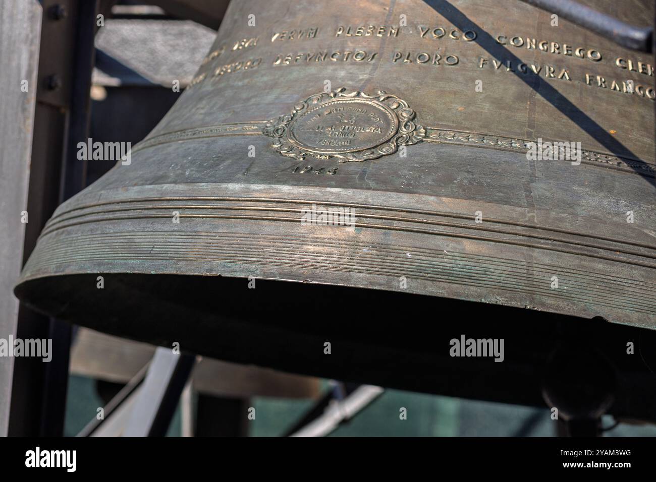 Large bronze bell with ornate details and latin inscription is hanging ...