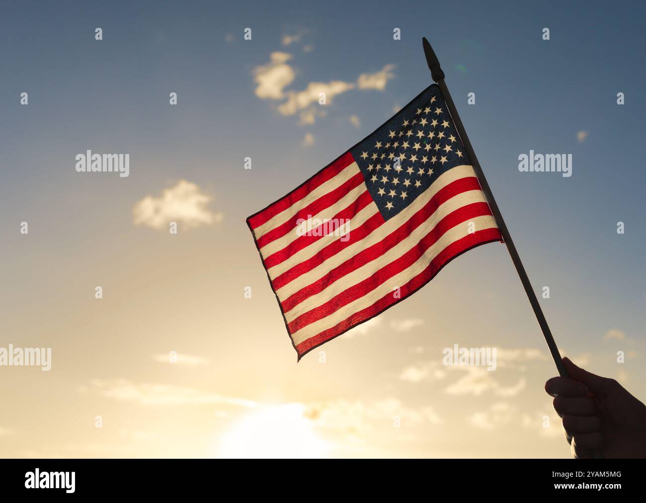 Hand holding American flag against sunset sky Stock Photo - Alamy