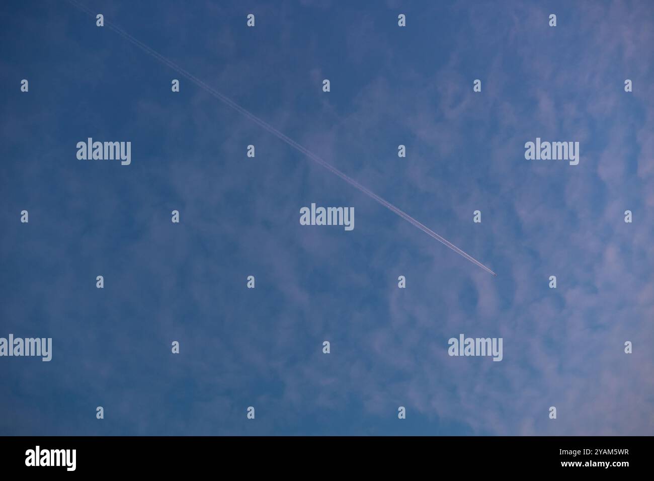 Airplane flying across the sky leaving a long vapor trail against a ...