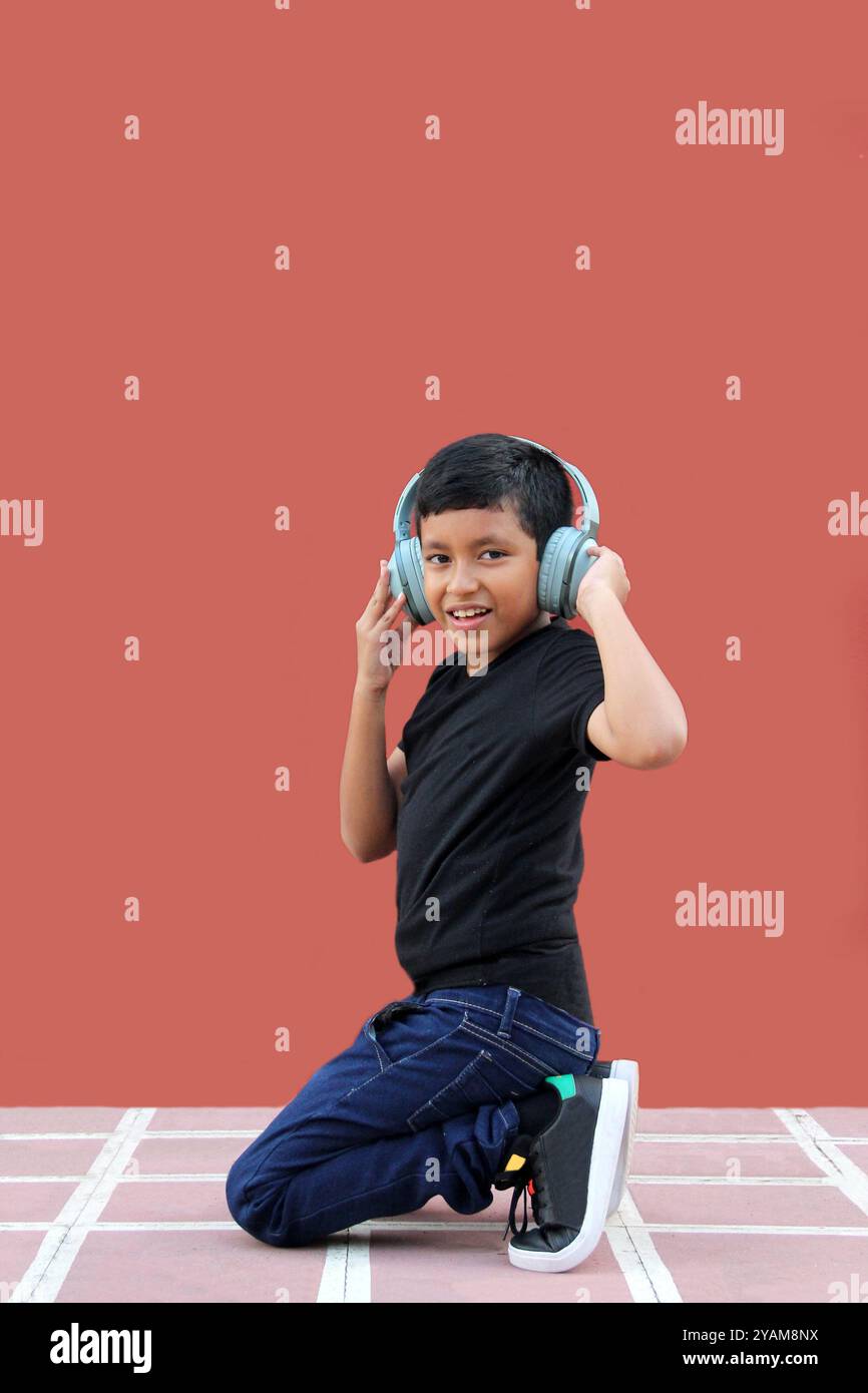 9-year-old dark-skinned Latino boy uses noise-isolating headphones for ...