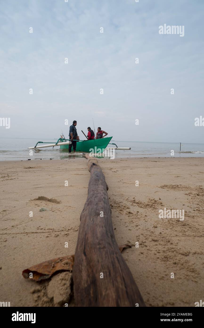 Photo of a boat with fishermen seen from the end of a long log on the ...