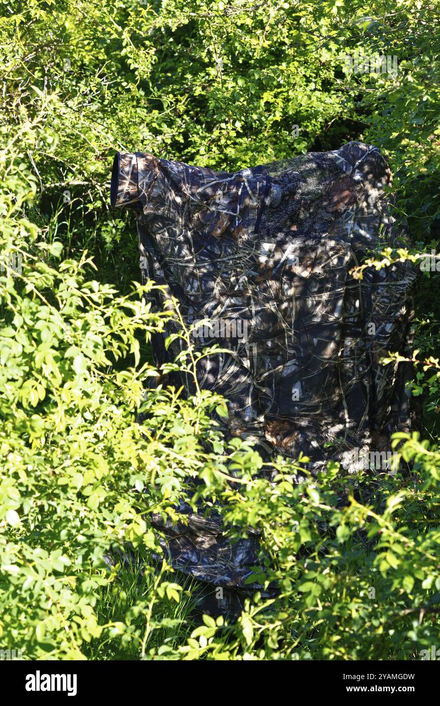 Nature photographer in camouflage at work, camouflage net in a dense ...