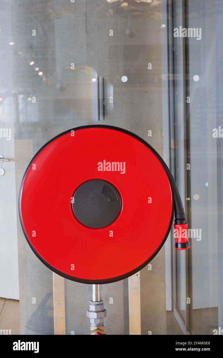 A striking red fire hose reel stands out against a contemporary and ...