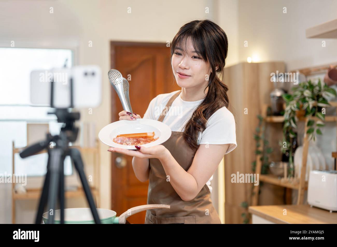 A pretty and happy young Asian female food content creator or chef in ...