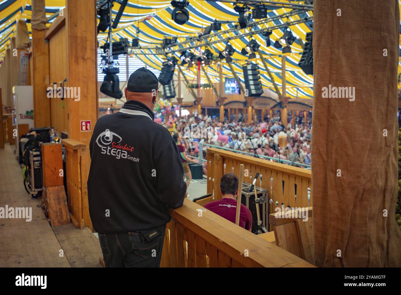 Man in security jumper standing in front of a busy event in a tent ...